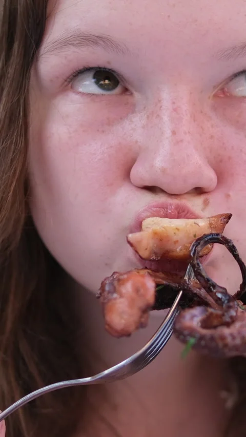 A girl eats an octopus squid with her mo... | Stock Video | Pond5