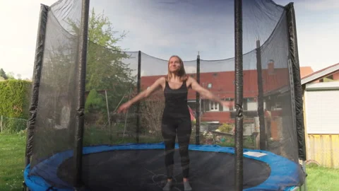 Girl is jumping on a trampoline in her b... | Stock Video | Pond5