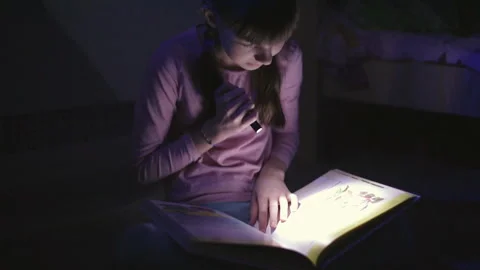 girl is reading a book with a flashlight... | Stock Video | Pond5