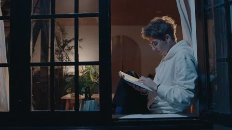 Girl Reading Book on Window Sill in the ... | Stock Video | Pond5