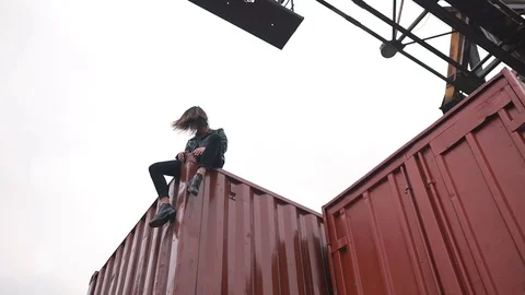 the girl sits on a freight container | Stock Video | Pond5
