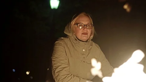 Girl sits at night before burning fire a... | Stock Video | Pond5