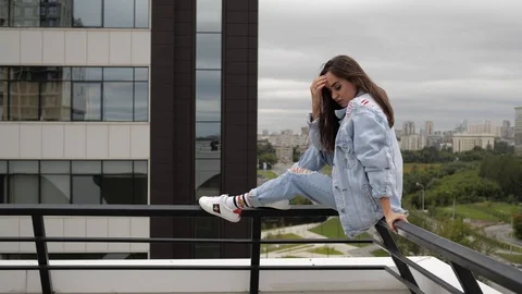 girl sitting on the railing of the roof | Stock Video | Pond5
