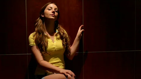 Girl sitting under Dramatic light | Stock Video | Pond5