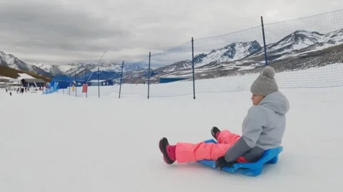 Girl sliding on a sled in a snowy mounta... | Stock Video | Pond5