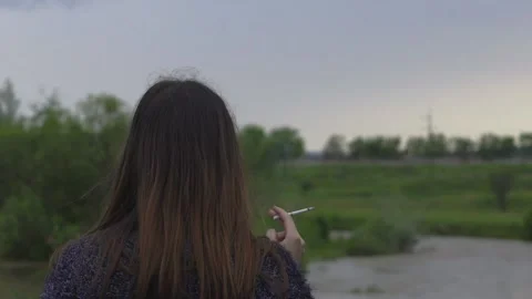 Girl smoking in nature by river slowmoti... | Stock Video | Pond5