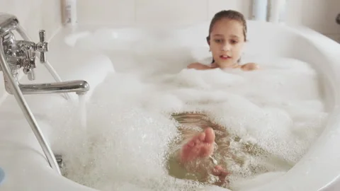 Girl squishes feet in a bathtub full of ... | Stock Video | Pond5