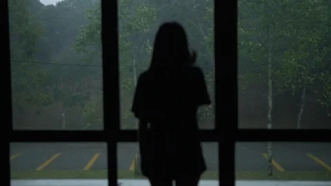A girl stands looking out a tall window ... | Stock Video | Pond5