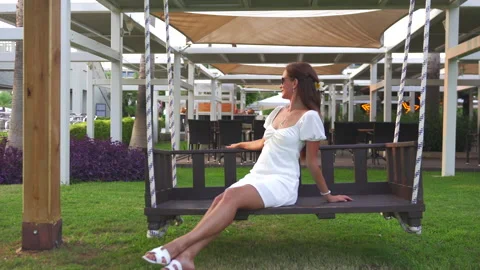 Girl in white riding on a hanging bench | Stock Video | Pond5