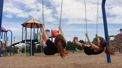 girls swinging high on a swing set | Stock Video | Pond5
