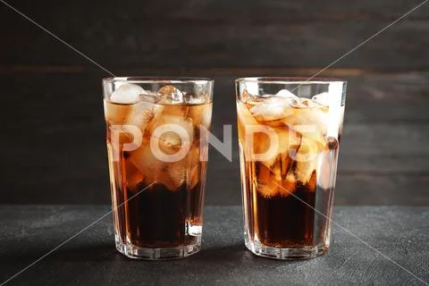 Photograph: Glasses of refreshing cola with ice cubes on table #235681292
