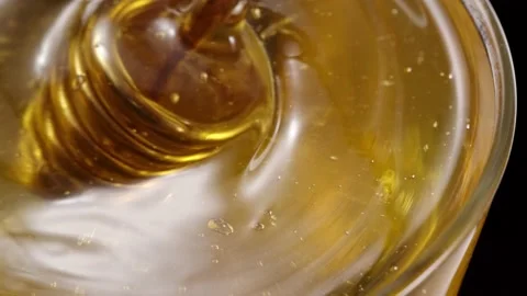 Golden honey dipper turning in glass jar | Stock Video | Pond5