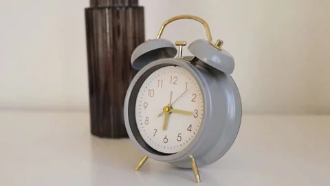 Gray alarm clock stands on a white table... | Stock Video | Pond5