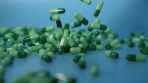 Green medicine capsules fall on a blue b... | Stock Video | Pond5