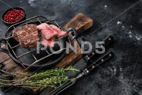 Grilled fillet mignon beef steak on a grill. Black background. Top view ...