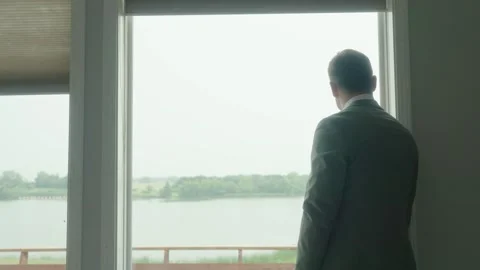 Groom in green suit looks out a window, ... | Stock Video | Pond5