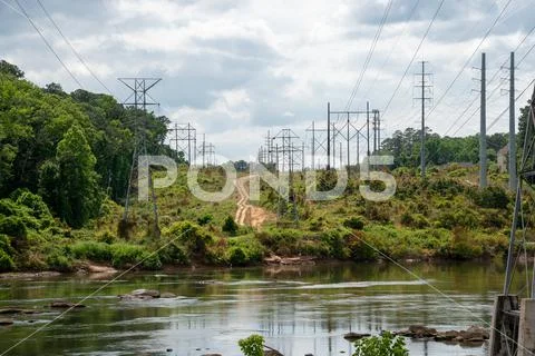 A group overhead high voltage power lines crossing a body of water ...