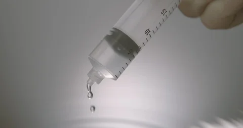 Hand dripping liquid from syringe onto a... | Stock Video | Pond5