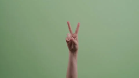 Hand Gesturing Peace Sign in Front of Gr... | Stock Video | Pond5