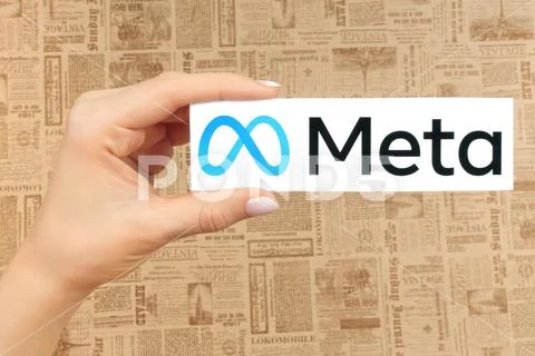 Hand holds Meta logo, on old newspaper background. Social media giant ...