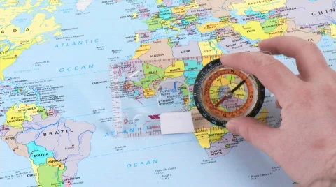 Hand moving a compass over a world map | Stock Video | Pond5