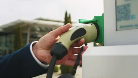 Hand pulling in cable from EV car charge... | Stock Video | Pond5