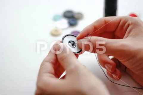 Hand sew a button with needle and thread. Closeup. Isolated on a white ...