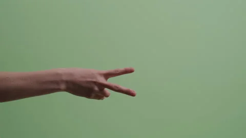 Hand Shows Peace Sign in Front of Green ... | Stock Video | Pond5