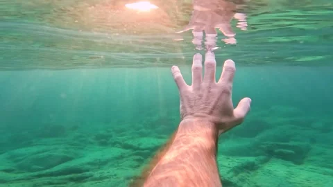 Hand underwater illuminated by sun rays | Stock Video | Pond5