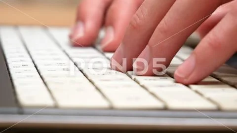 Hands, fingers fast typing on a white laptop keyboard, side view ...