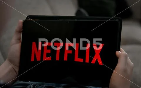 Hands holding tablet with Netflix logo on a black screen. Stock Image ...