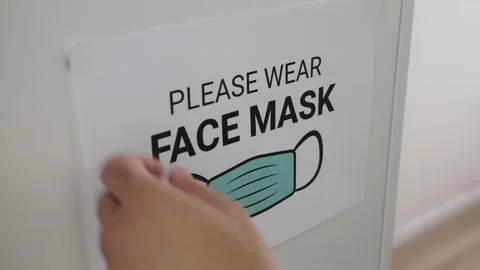 Hands take down a sign with please wear ... | Stock Video | Pond5