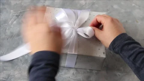 Hands untie a bow on a present on a tabl... | Stock Video | Pond5