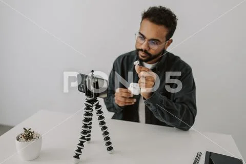 Handsome black man vlogger sitting in living room and talking to phone ...
