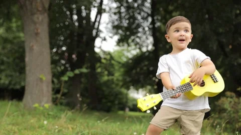 Handsome boy playing music in the park o... | Stock Video | Pond5