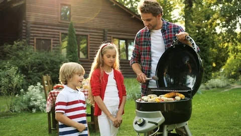 Handsome father grilling on the barbecue... | Stock Video | Pond5