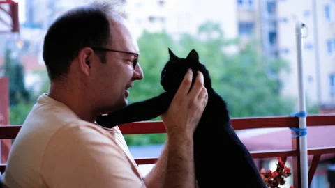 Handsome man cuddling black cat pet on a... | Stock Video | Pond5