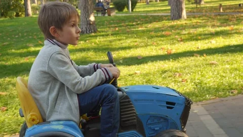 Happy boy riding on toy tractor at park.... | Stock Video | Pond5
