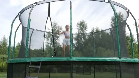 Happy child girl jumping on a trampoline... | Stock Video | Pond5
