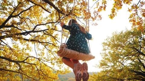 Happy child girl on swing at golden suns... | Stock Video | Pond5