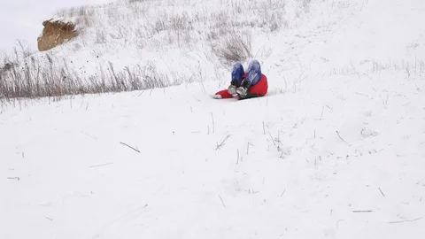 happy child slides on snow slide on sled... | Stock Video | Pond5
