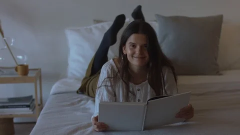 Happy girl reading paper book lying in b... | Stock Video | Pond5