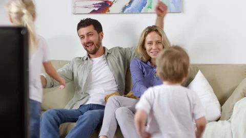 Happy Kids Joining Parents on Sofa | Stock Video | Pond5