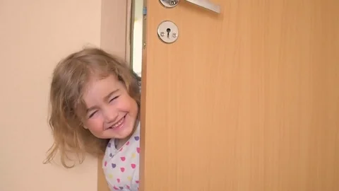 Happy little girl peeking out from behin... | Stock Video | Pond5