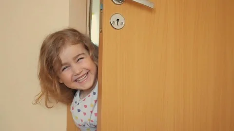Happy little girl peeking out from behin... | Stock Video | Pond5