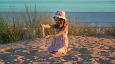 Happy little girl plays with sand on bea... | Stock Video | Pond5