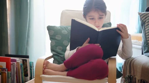 happy little girl reading a book sitting... | Stock Video | Pond5