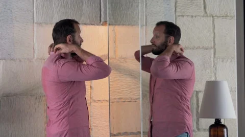 Happy man putting on shirt in front of m... | Stock Video | Pond5