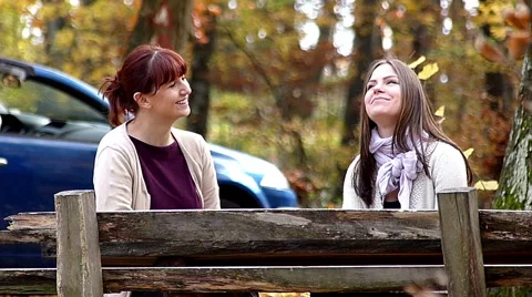 Happy young girls talking on bench in fo... | Stock Video | Pond5