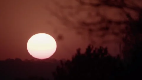 A hazy sunset with a large, glowing sun ... | Stock Video | Pond5